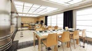 Quarto de hotel com área de refeições, cozinha e uma janela grande.