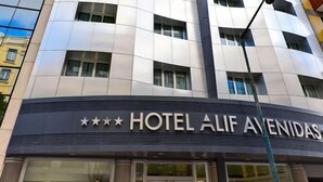 Um edifício moderno de hotel com uma placa que diz 'HOTEL ALIF AVENIDAS'.