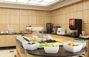 Buffet de café da manhã em hotel, com diversos alimentos e estação de café.