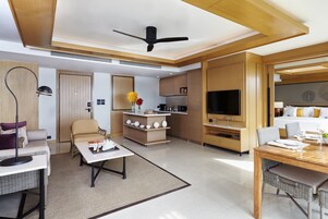 Quarto de hotel moderno com área de refeições, cozinha compacta e uma cama grande.