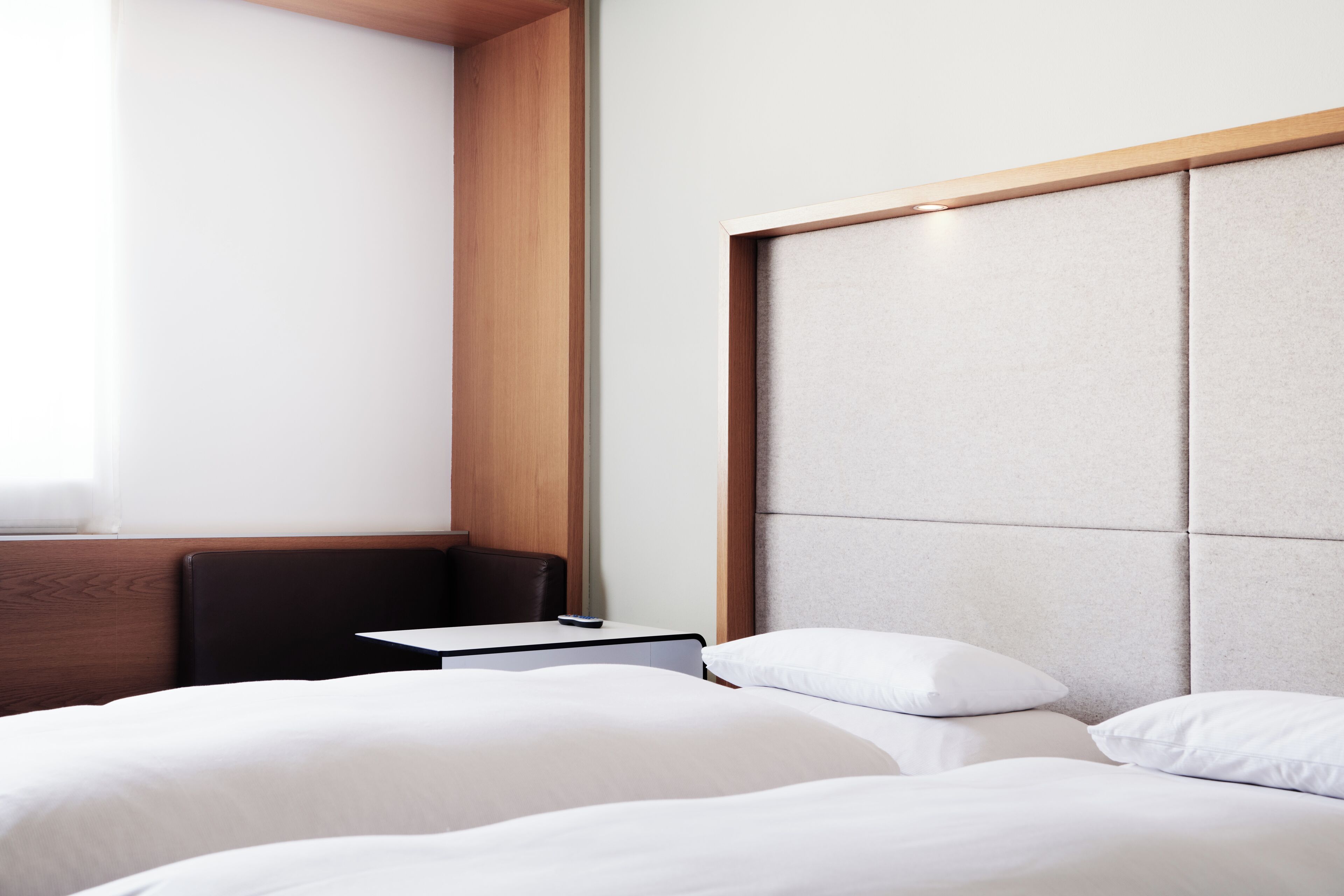Quarto de hotel com cama, mesa de cabeceira, uma cadeira e cabeceira.