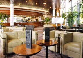 Um lobby de hotel com sofás de couro, área de bar e balcão de recepção.