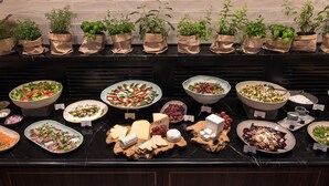 Buffet com diversos alimentos e plantas em vasos.