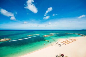 Uma praia com águas turquesa cristalinas, um farol e uma fileira de guarda-sóis.
