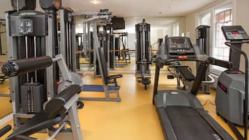 Uma academia com diversos equipamentos de exercícios, incluindo esteira e aparelhos de musculação.