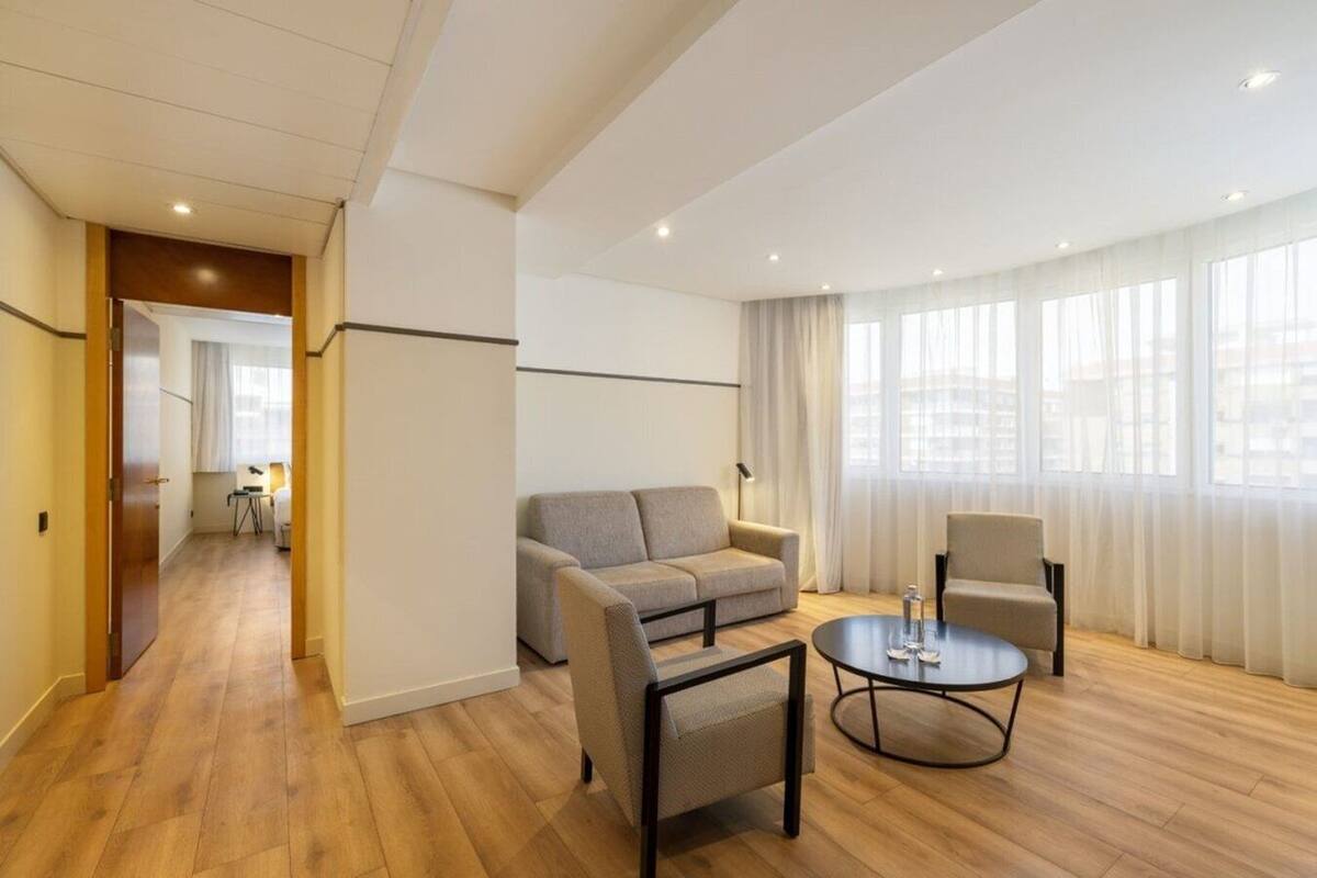 Quarto de hotel moderno com sofá, poltrona e mesa de centro.