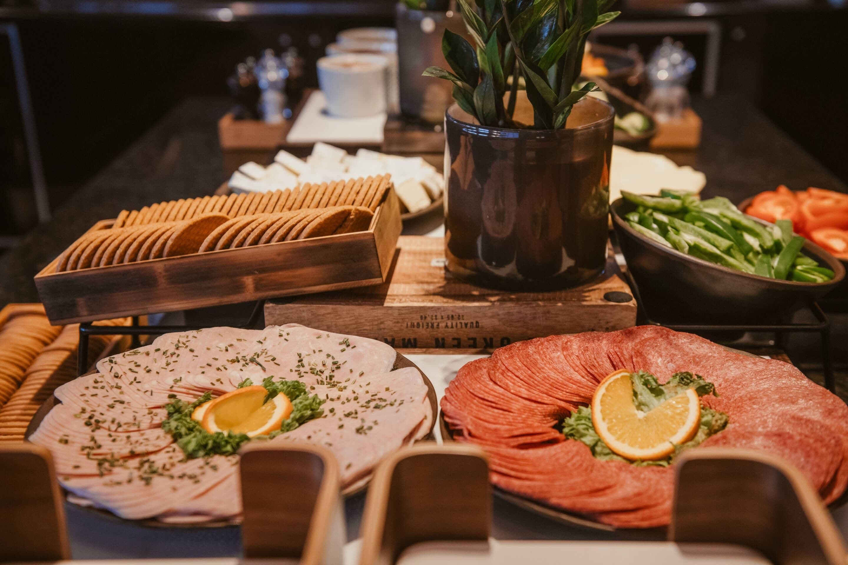 Uma mesa de buffet com diversos alimentos e uma planta em vaso.