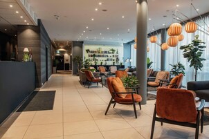 Um lobby moderno com balcão de recepção, área de estar e uma estante cheia de livros.
