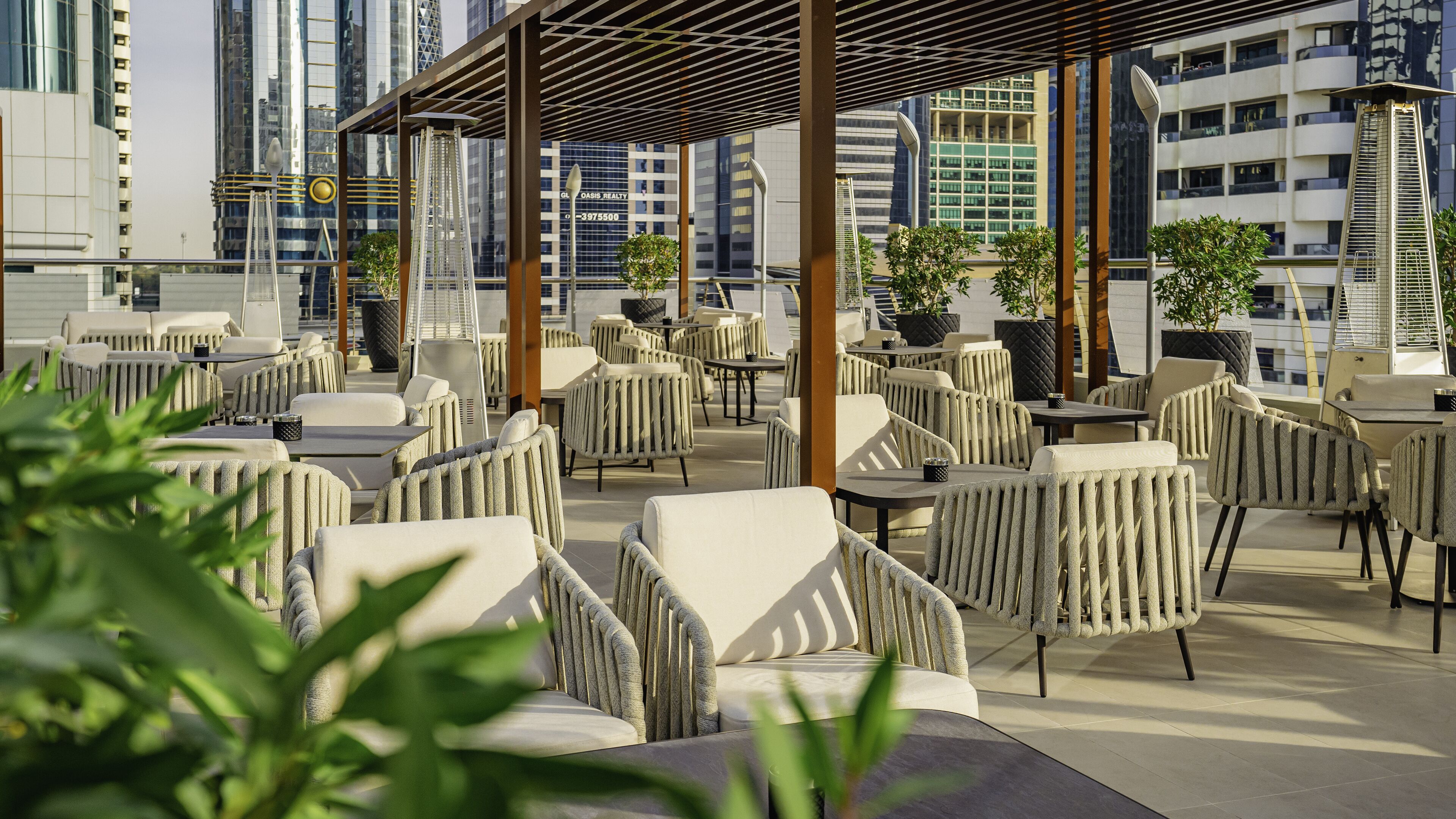 Terraço no telhado com área de estar ao ar livre, plantas em vasos e vista dos edifícios altos ao redor.