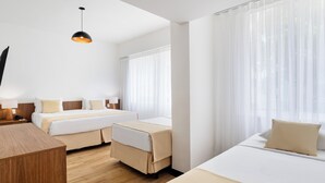 Quarto de hotel com duas camas, uma escrivaninha de madeira e uma luminária pendente.