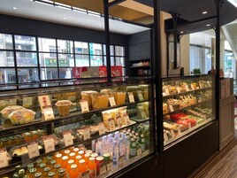 Vitrine refrigerada em loja, com diversos produtos embalados e bebidas.