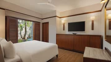Quarto com cama, televisão, ventilador de teto e vista para o exterior.