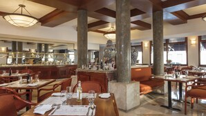 Um restaurante amplo com pé direito alto, pilares imponentes e diversas opções de assento, incluindo mesas e cabines.