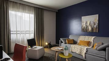 Uma sala de estar moderna com sofá cinzento, poltrona vermelha e mesa amarela.