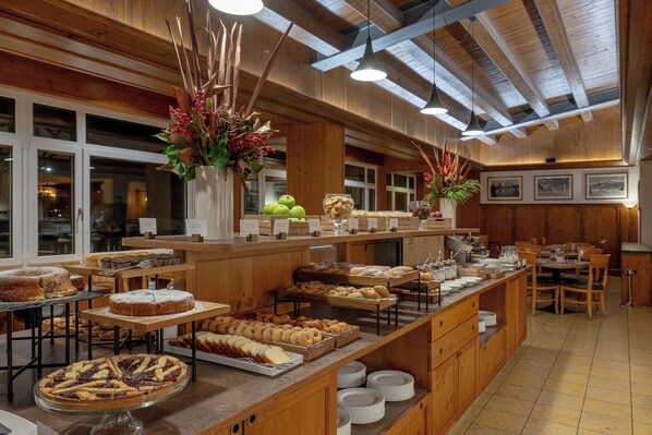 Uma área de buffet com diversos alimentos, incluindo tortas, doces e frutas.