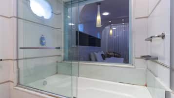 Casa de banho moderna com cabine de vidro, banheira e interior visível através do vidro.
