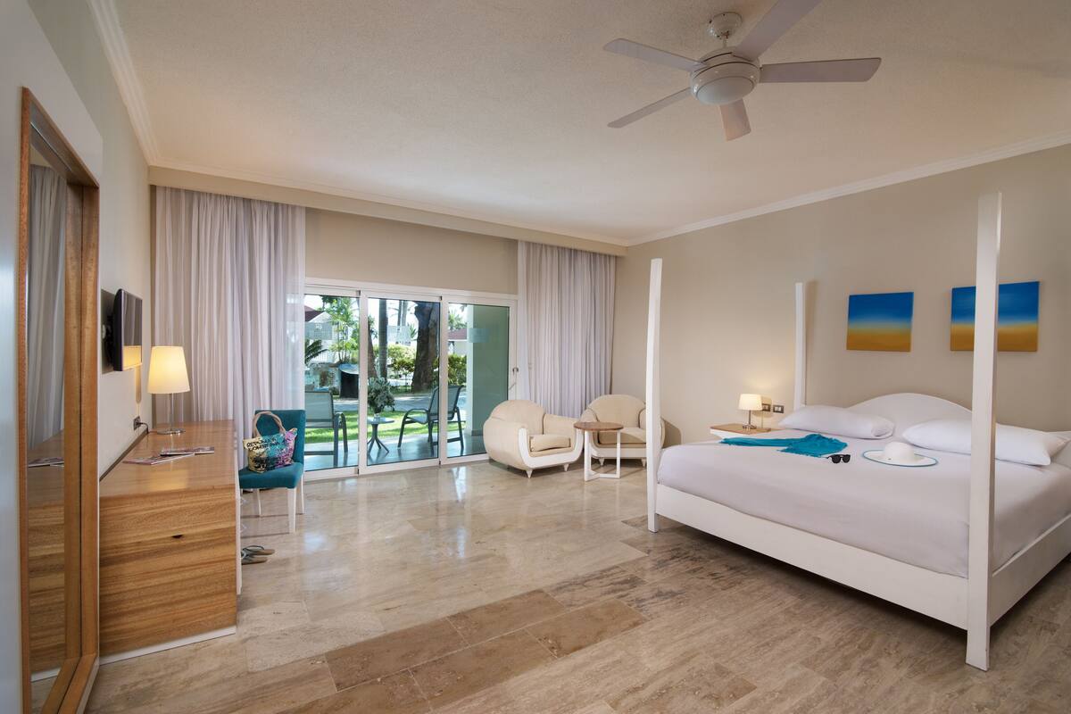 Quarto de hotel com cama, escrivaninha, cadeira e vista para o exterior.