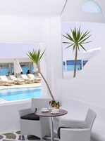 Área da piscina com espreguiçadeiras e uma mesa com copos e uma planta.