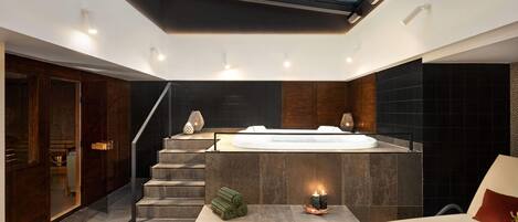 Uma área de spa moderna com hidromassagem, um espaço para sentar e uma escada que leva a uma porta de madeira.