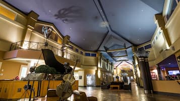 Um hall espaçoso com teto alto, um piano de cauda e um grande lustre.