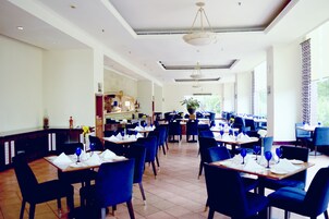 Um restaurante espaçoso com pé-direito alto, lustres modernos e uma longa área de jantar com mesas dispostas para vários convidados.