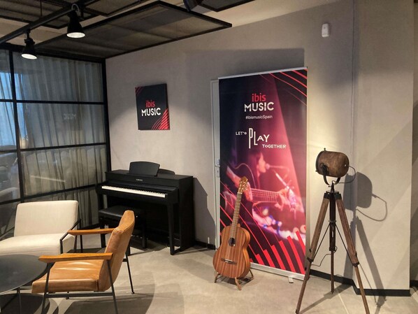 Quarto com tema musical, com um piano, uma guitarra, uma cadeira e um cartaz divulgando eventos musicais.