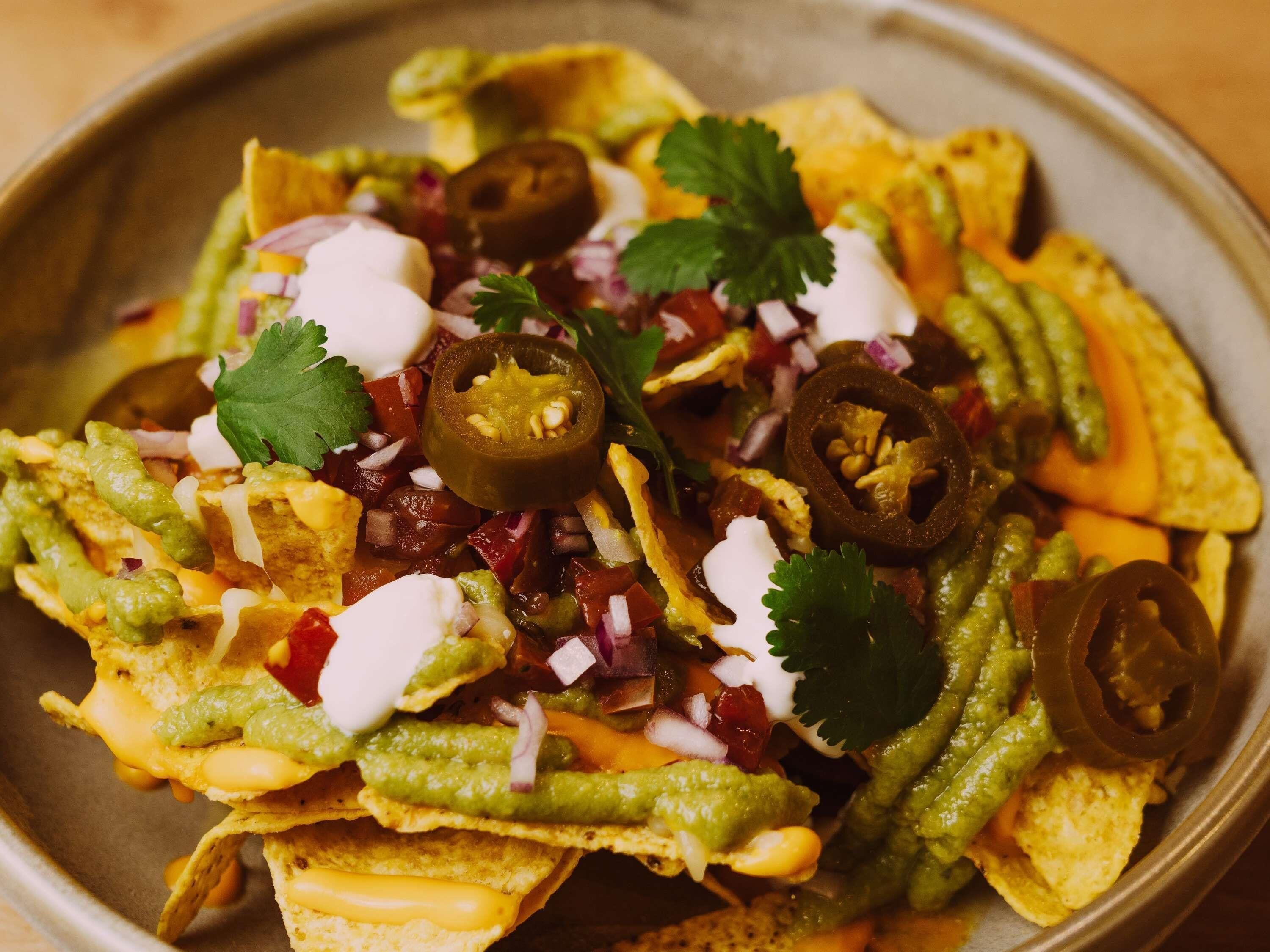 Nachos cobertos com guacamole, creme azedo, jalapeños e coentro.