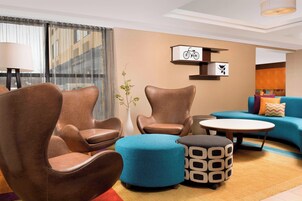 Uma sala de estar moderna com poltronas de couro, um sofá azul e um banquinho estampado.