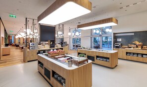 Um café moderno com balcões de madeira, uma máquina de café e diversos alimentos expostos.