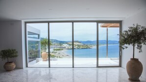 Quarto espaçoso com uma grande porta de vidro deslizante que dá para uma varanda com vista para o mar.
