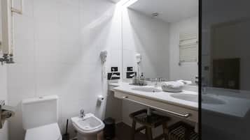 Uma casa de banho moderna com sanita, bidé, lavatório e espelho.