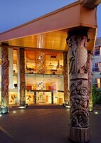 Uma entrada de hotel com fachada imponente, vários andares e detalhadas esculturas em pedra.