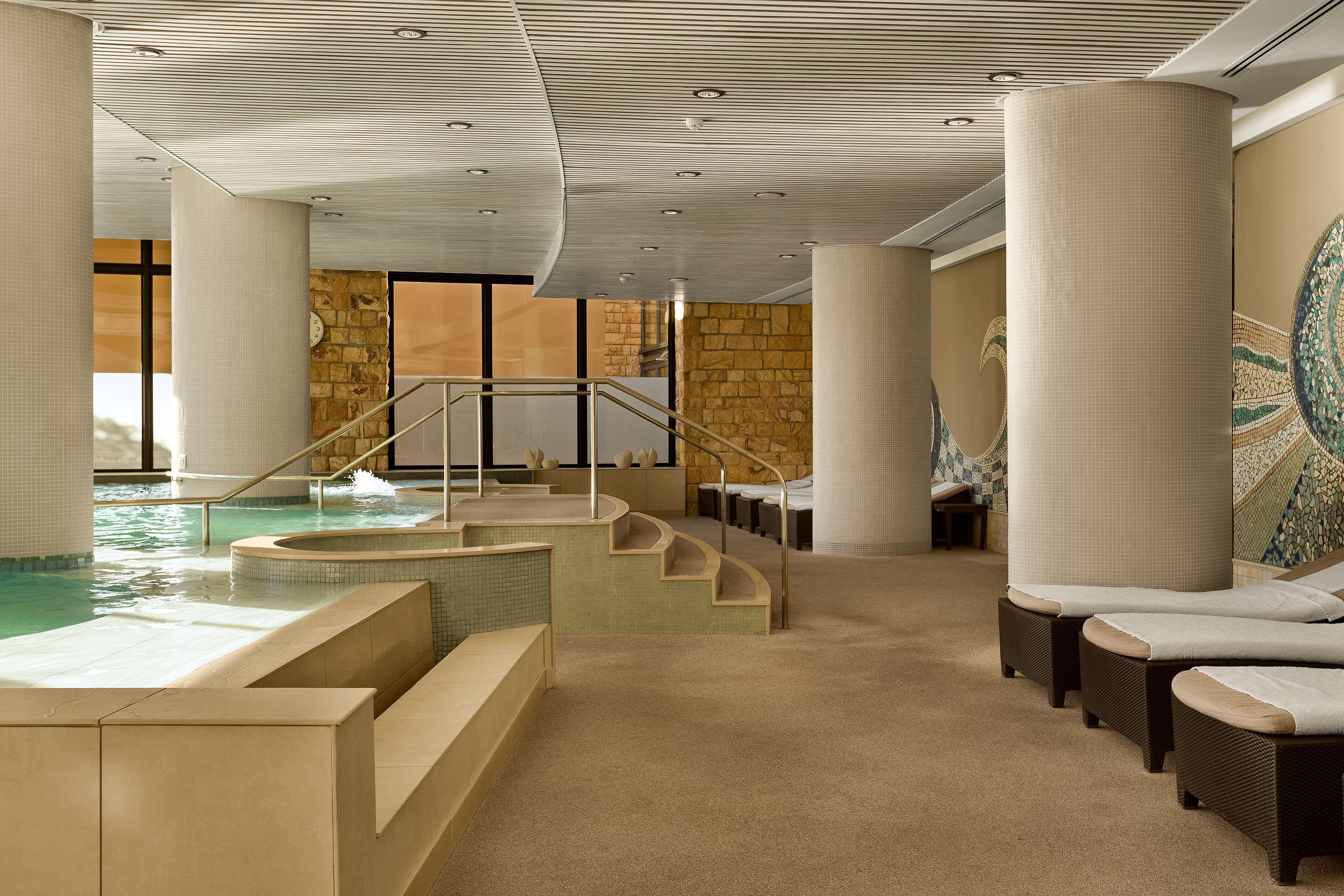 Área de spa com hidromassagem, escada para um nível superior e espreguiçadeiras.