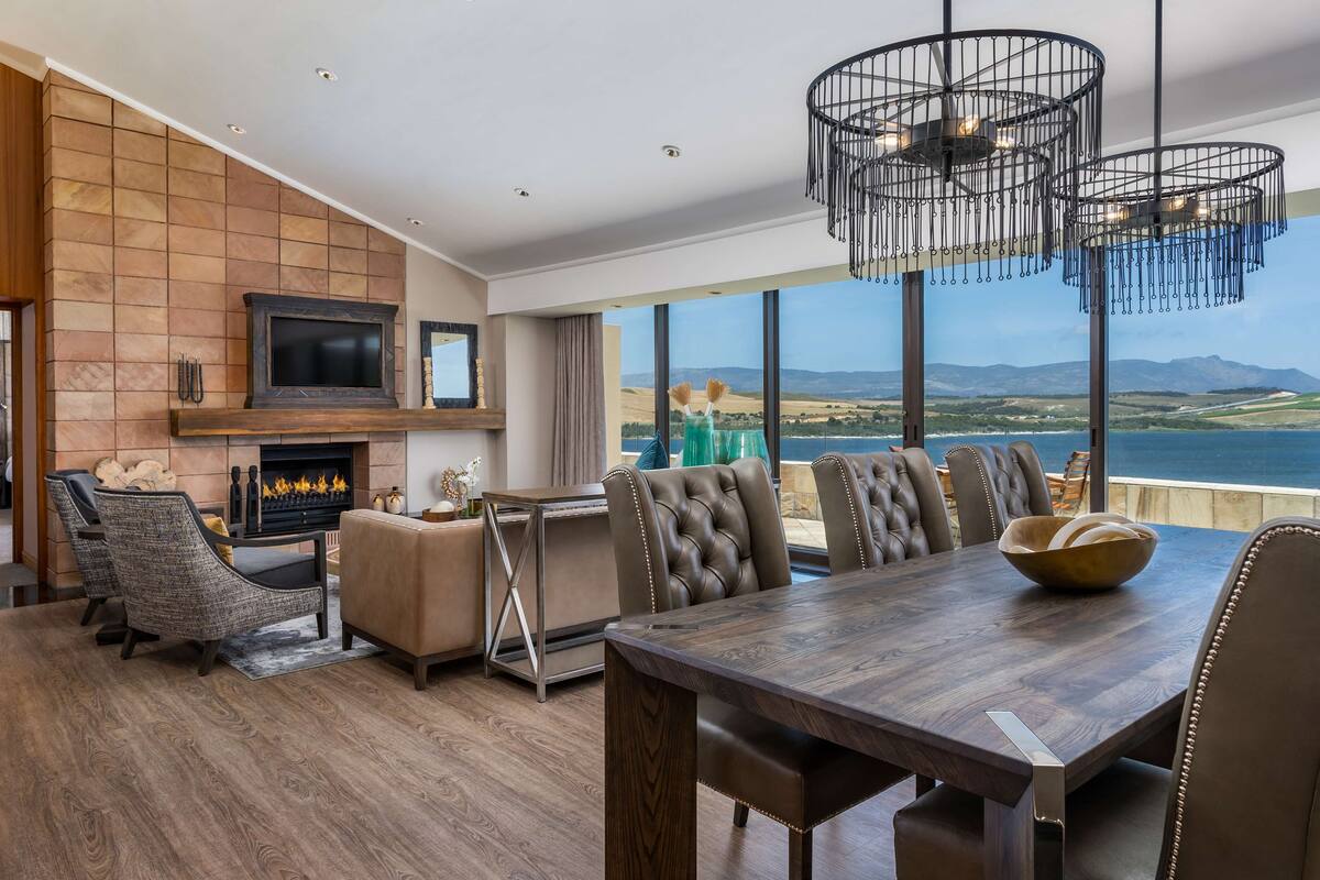 Uma sala de jantar moderna com uma grande mesa de madeira, cadeiras de couro e vista para o mar.