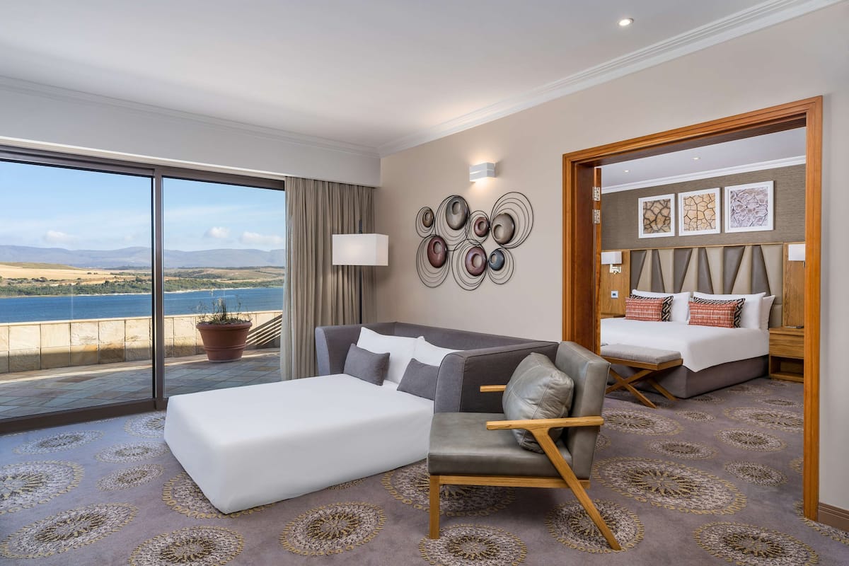 Quarto de hotel moderno com uma varanda ampla, um sofá, uma poltrona e uma cama.