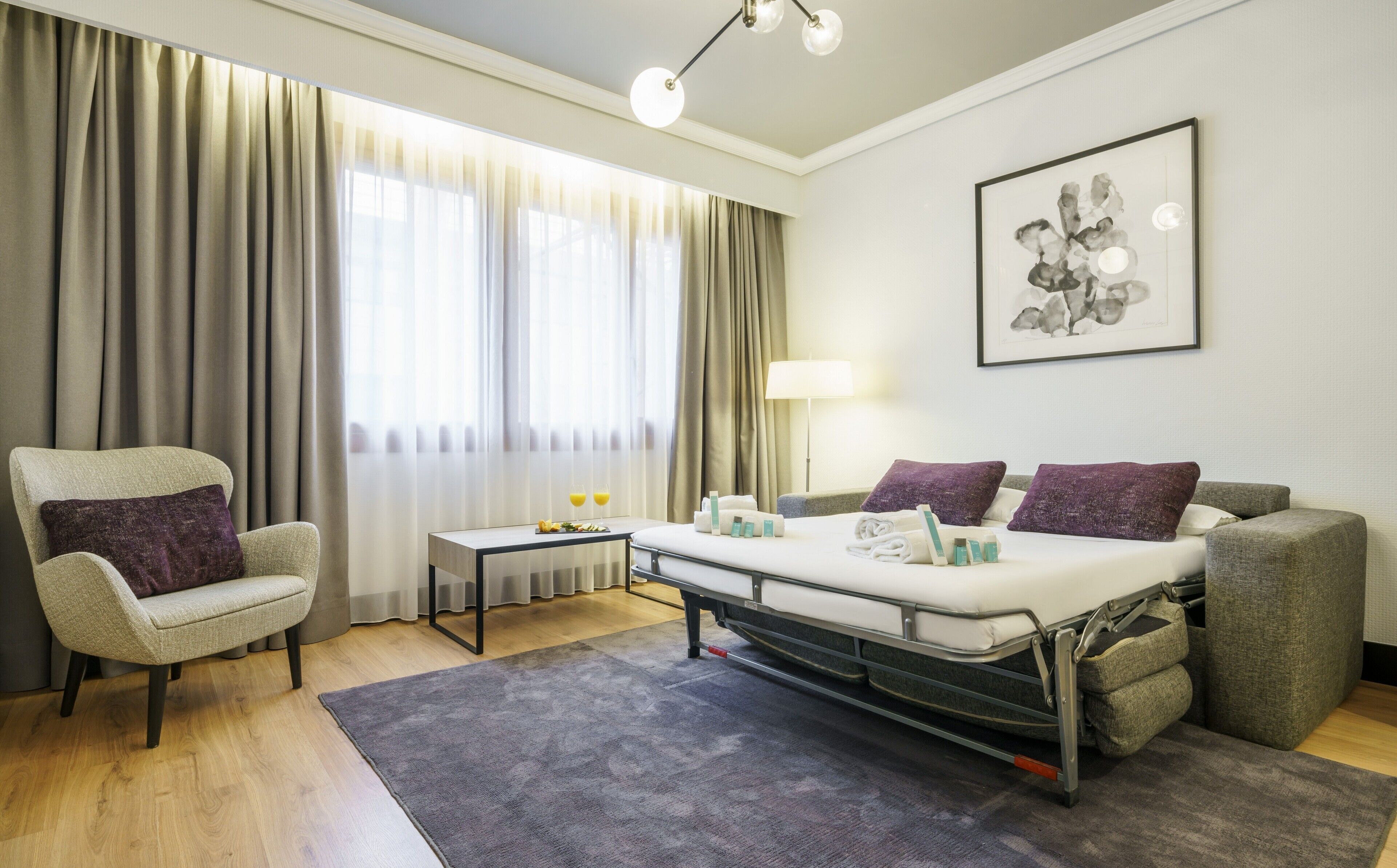 Quarto de hotel com cama, uma cadeira, uma mesa e um abajur.