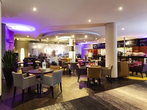 Restaurante moderno com mesas redondas, cadeiras e vista para a cidade.
