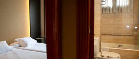 Quarto de hotel com duas camas, banheiro com banheira e chuveiro.