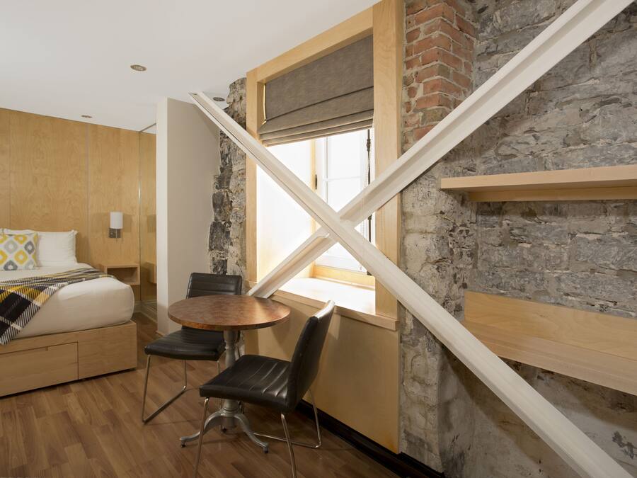 Quarto moderno com cama, mesa de jantar e uma cadeira. Há uma janela com vista para o exterior.