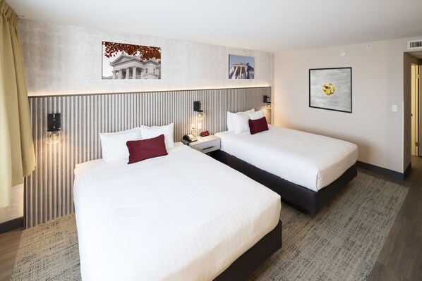 Quarto de hotel com duas camas, cabeceira listrada e um quadro pendurado na parede.