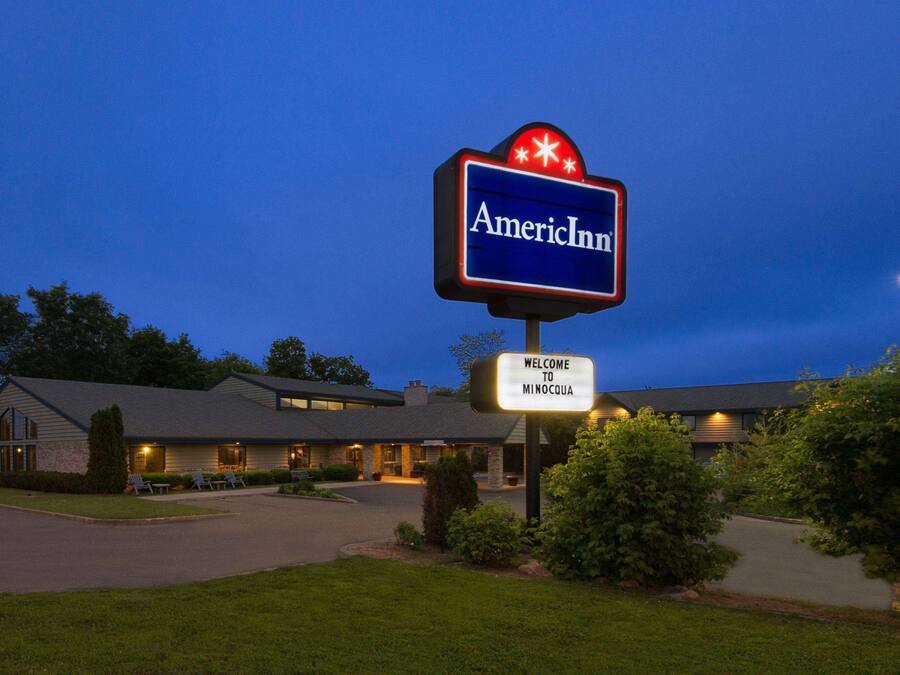 Placa de hotel com o nome "AmericInn" e uma placa de boas-vindas para "Minocqua".