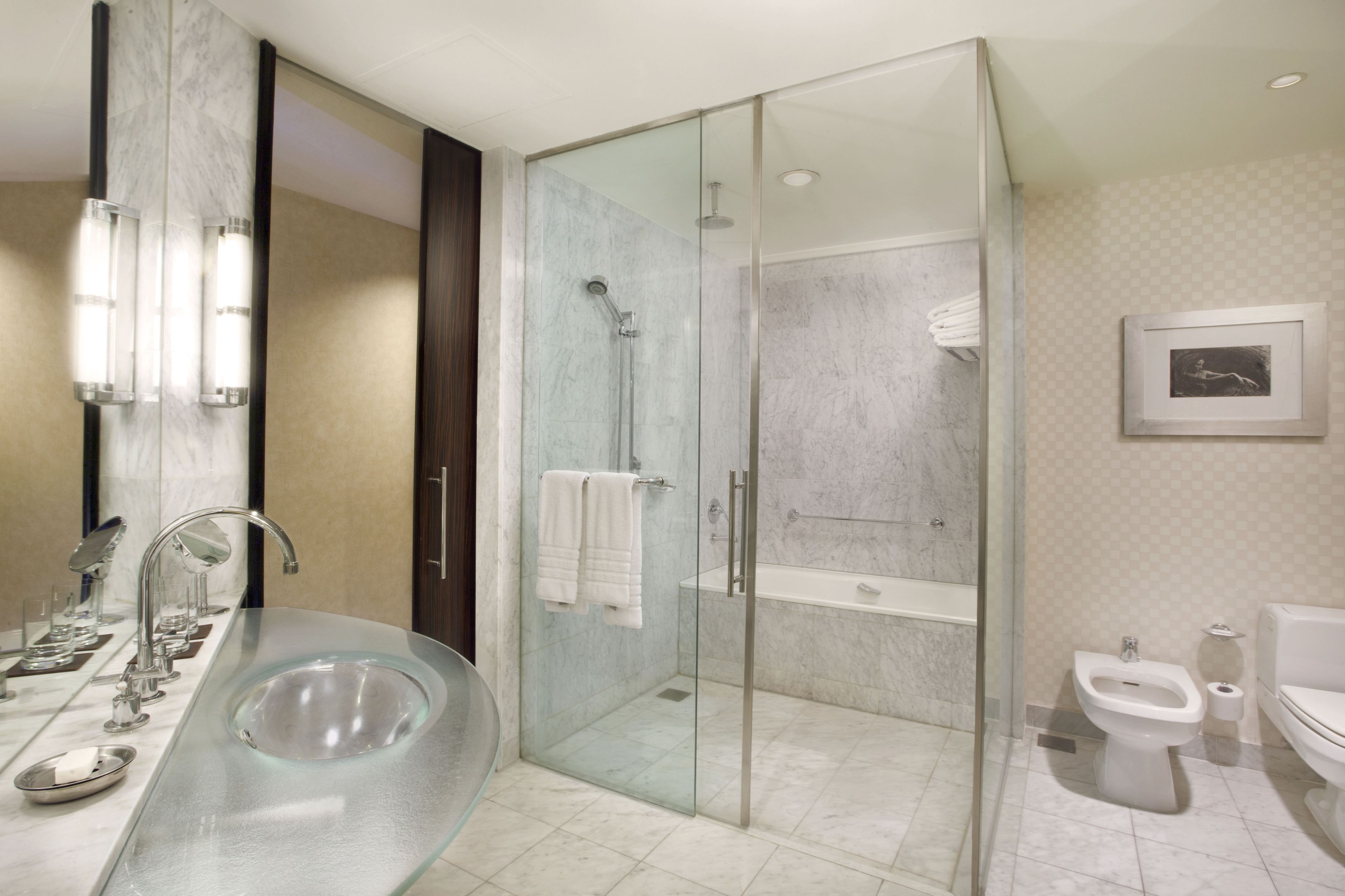 Uma casa de banho moderna com cabine de duche em vidro, lavatório generoso em vidro e espaço sanitário separado.
