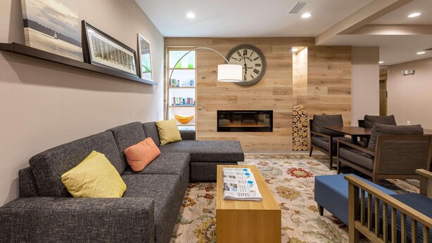 Uma sala de estar moderna com um sof á modular, uma mesa de centro, uma lareira e um relógio na parede.