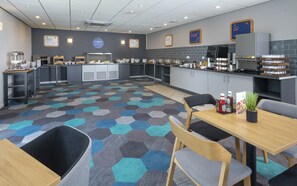 Uma área de café da manhã moderna com piso de padrão hexagonal, um buffet e uma máquina de café.