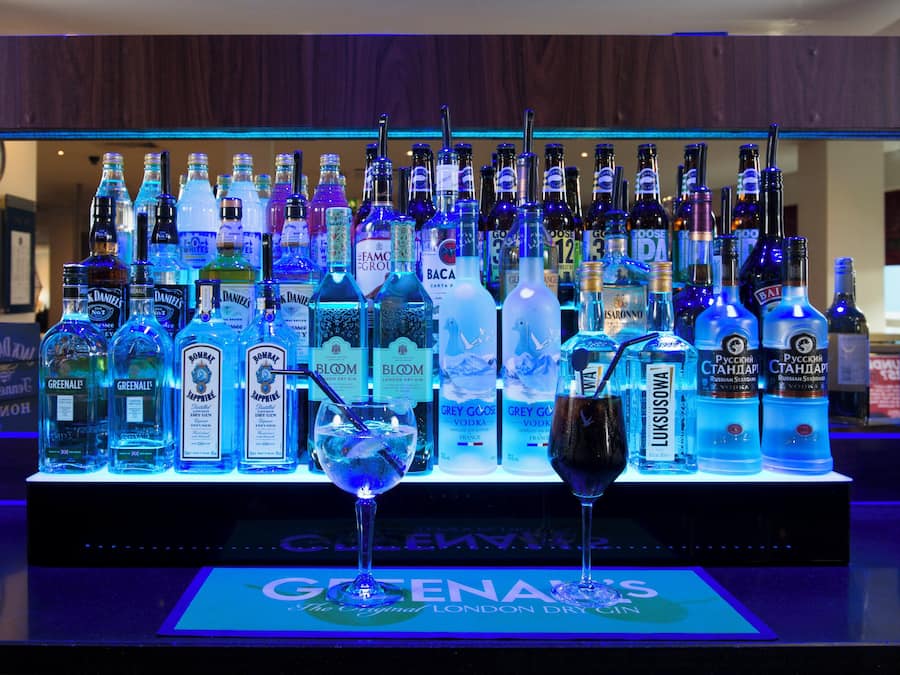 Bar com diversas garrafas de bebidas e um copo com canudo.