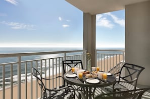 Mesa de varanda com itens de café da manhã e vista para o oceano.