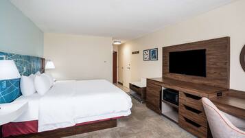 Quarto de hotel com cama, escrivaninha, televisão e micro-ondas.