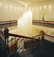 Uma escadaria imponente com grades de ferro ricamente decoradas e um lustre.