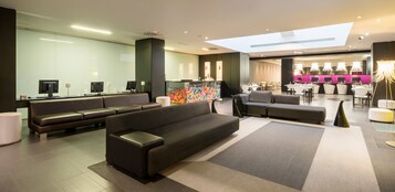 Um hall de hotel moderno com balcão de recepção, área de estar e um espaço de brincar colorido para crianças.