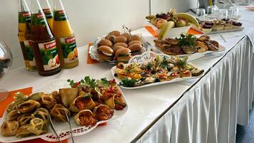 Uma mesa de buffet com diversos alimentos, incluindo sanduíches, doces e uma seleção de sucos.